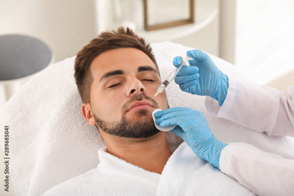 Handsome man receiving filler injection in beauty salon Stock Photo ...