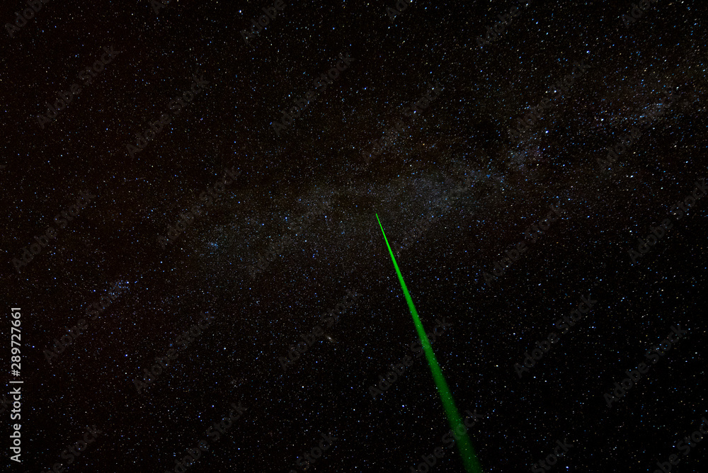 A laser beam shoots into the night sky. Part of the Milky Way visible ...