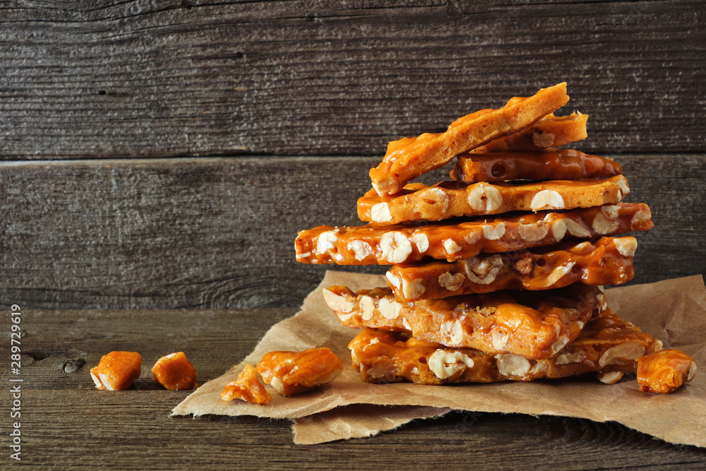 Stack of traditional peanut brittle candy pieces against a rustic wood ...