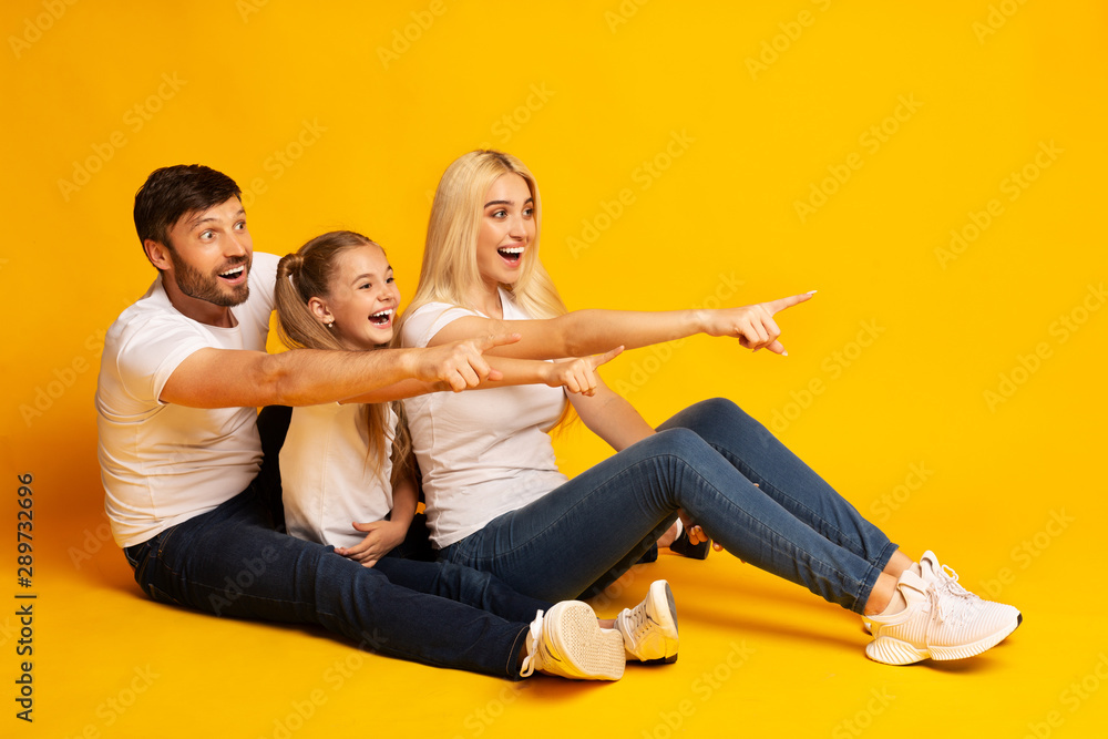 Family Pointing Fingers Aside Sitting On Floor, Yellow Background Stock ...