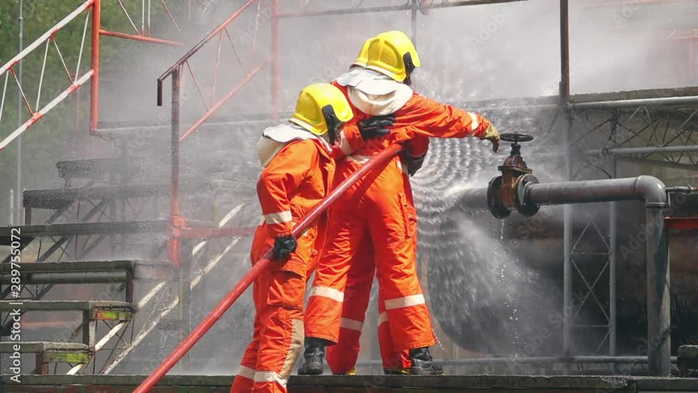 HD Slow motion wide shot Three firefighter in fire suit using water ...