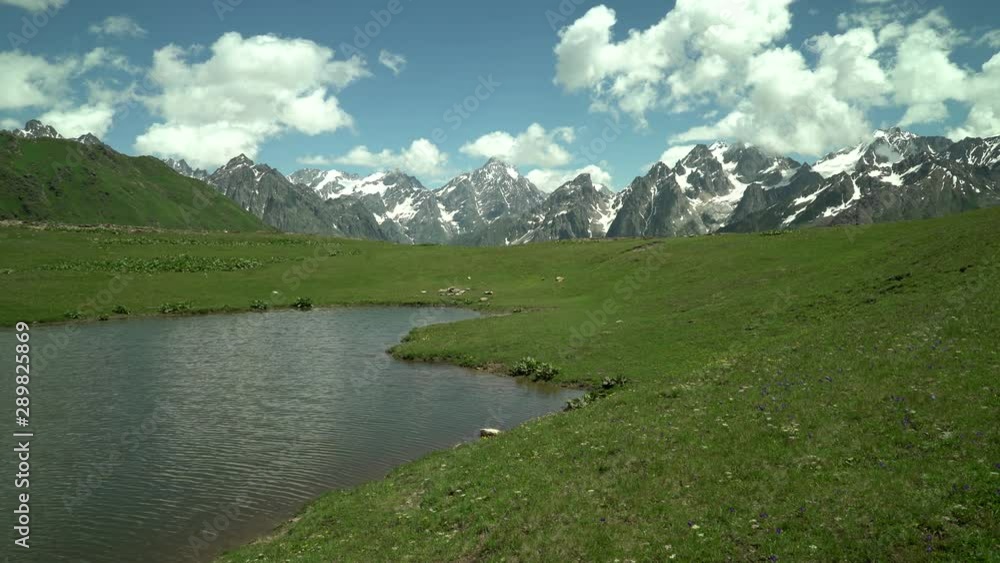 Clouds reflected in mountain lake. Snow capped mountain peaks in the ...