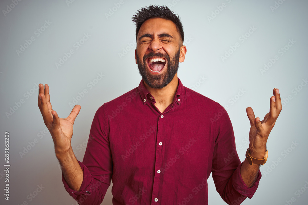 Young indian man wearing red elegant shirt standing over isolated grey ...