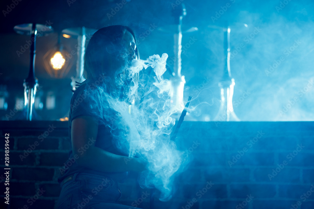 Beautiful woman in night club smoke hookah or shisha bar, blue ...