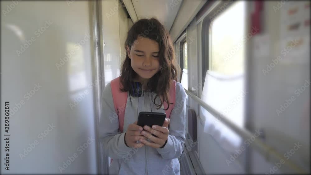 teen girl walks on a train compartment car with a backpack and a ...