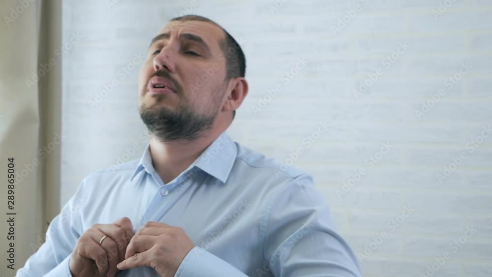 Man's hands buttoning a white shirt. Man with a beard dressing wear ...