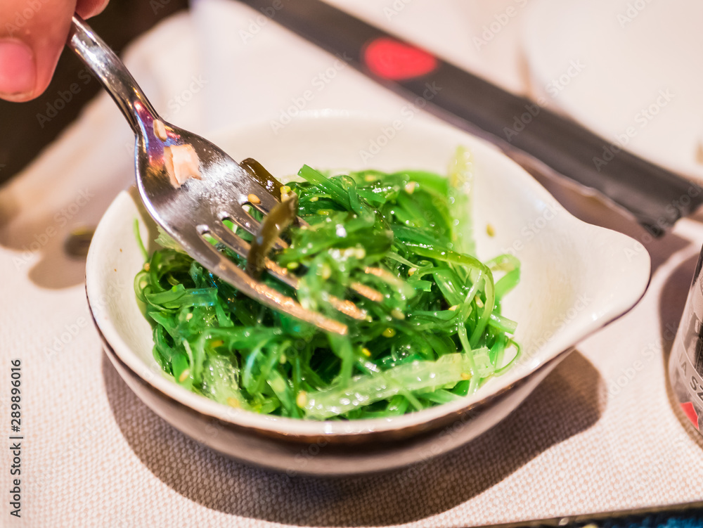Typical Japanese dish of algae with sesame and soy sauce, in a ceramic ...