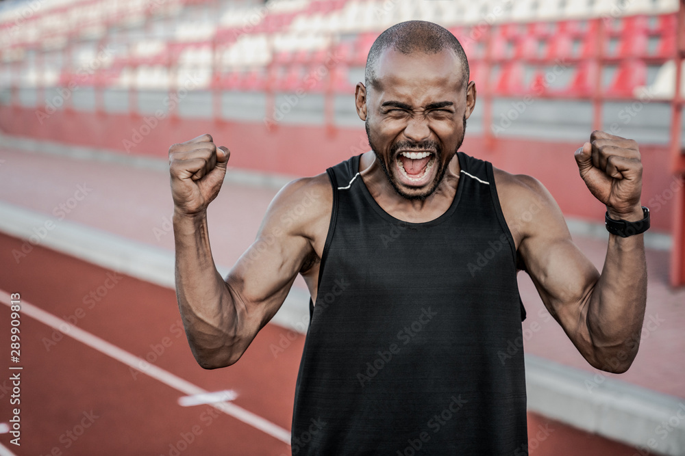 Happy male athlete sprinter in sport clothes emotionally rejoices ...