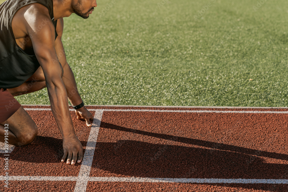 Side view cropped shot of sprinter about to start a race at stadium ...