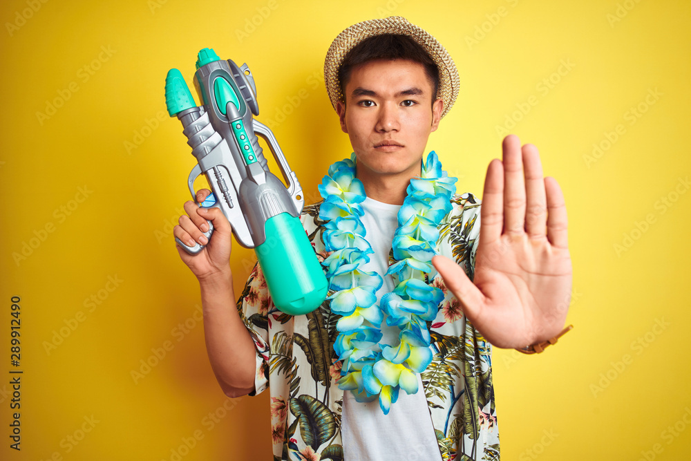 Asian chinese man wearing floral hawaian lei and water gun over ...
