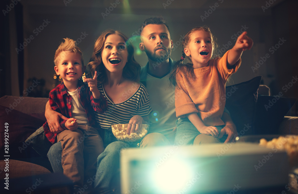 family mother father and children watching projector, TV, movies with ...