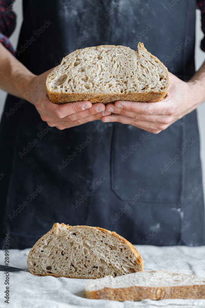 male baker demonstrates freshly baked sourdough bread at baking lesson ...