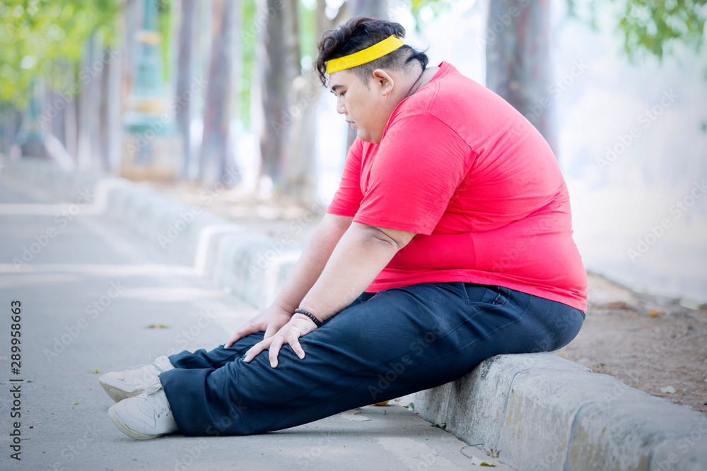 Obese man looks tired after running in the park Stock Photo | Adobe Stock