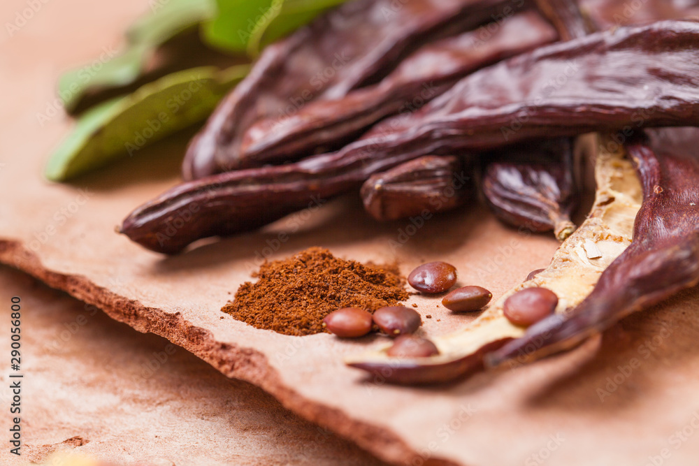 Carob. Organic carob pods with seeds and leaves on tree bark table ...