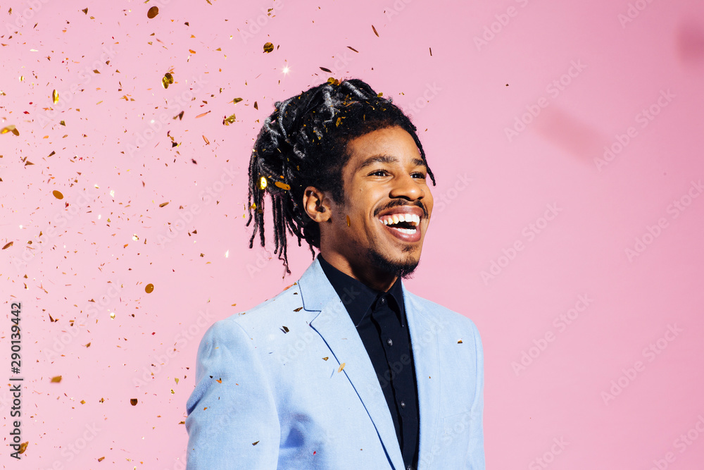 Portrait of a man with cool hair laughing, against studio background ...