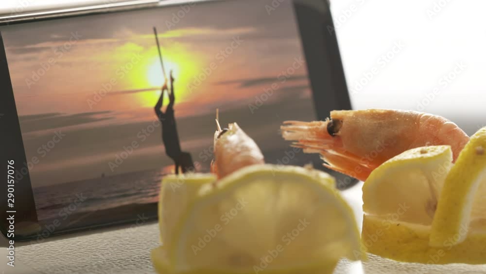 Frozen shrimps watching beach summer vacation video on mobile phone ...