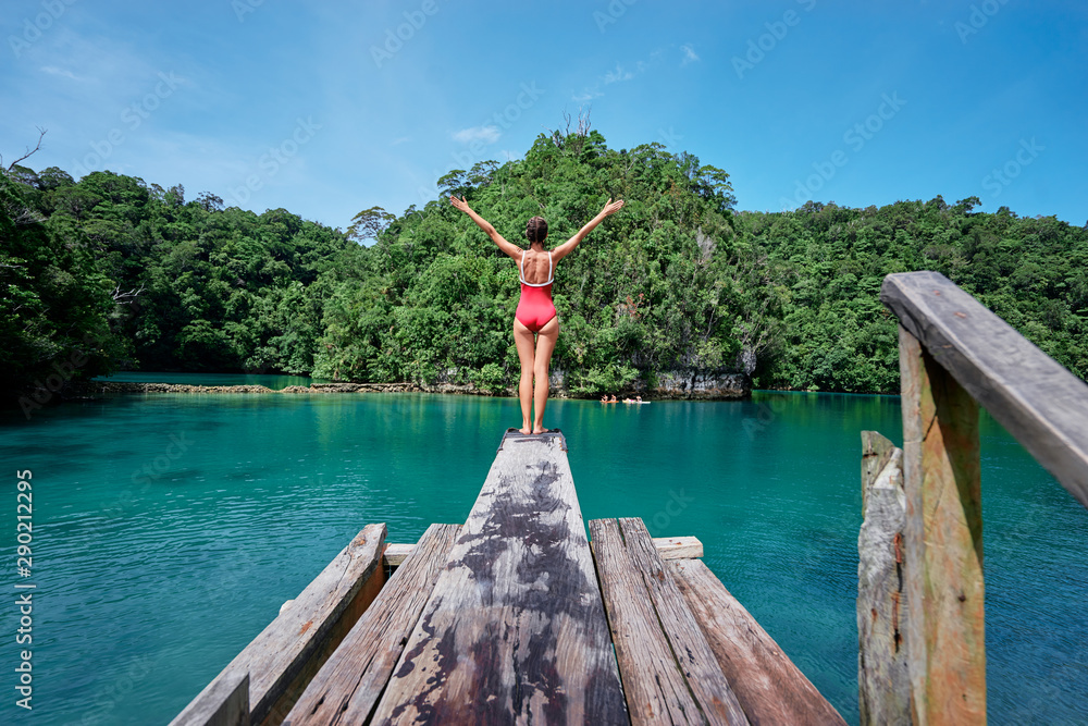 Vacation and activity. Young woman in swimsuit enjoying blue tropical ...