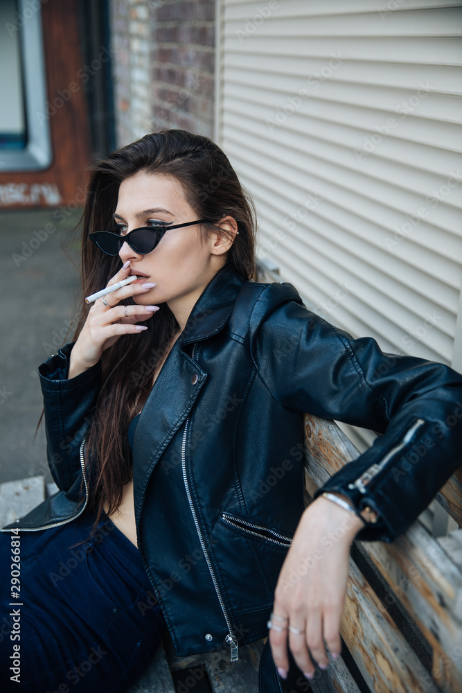 young girl in a leather jacket smokes cigarettes, rock style, cheeky ...