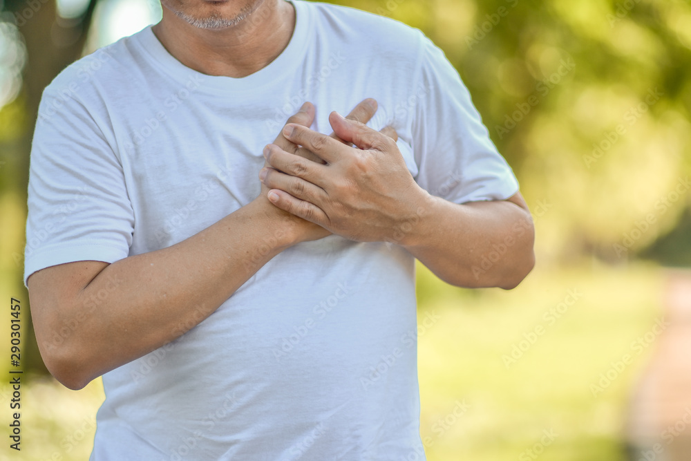 Senior man heart disease holds his hand in his heart while exercising ...