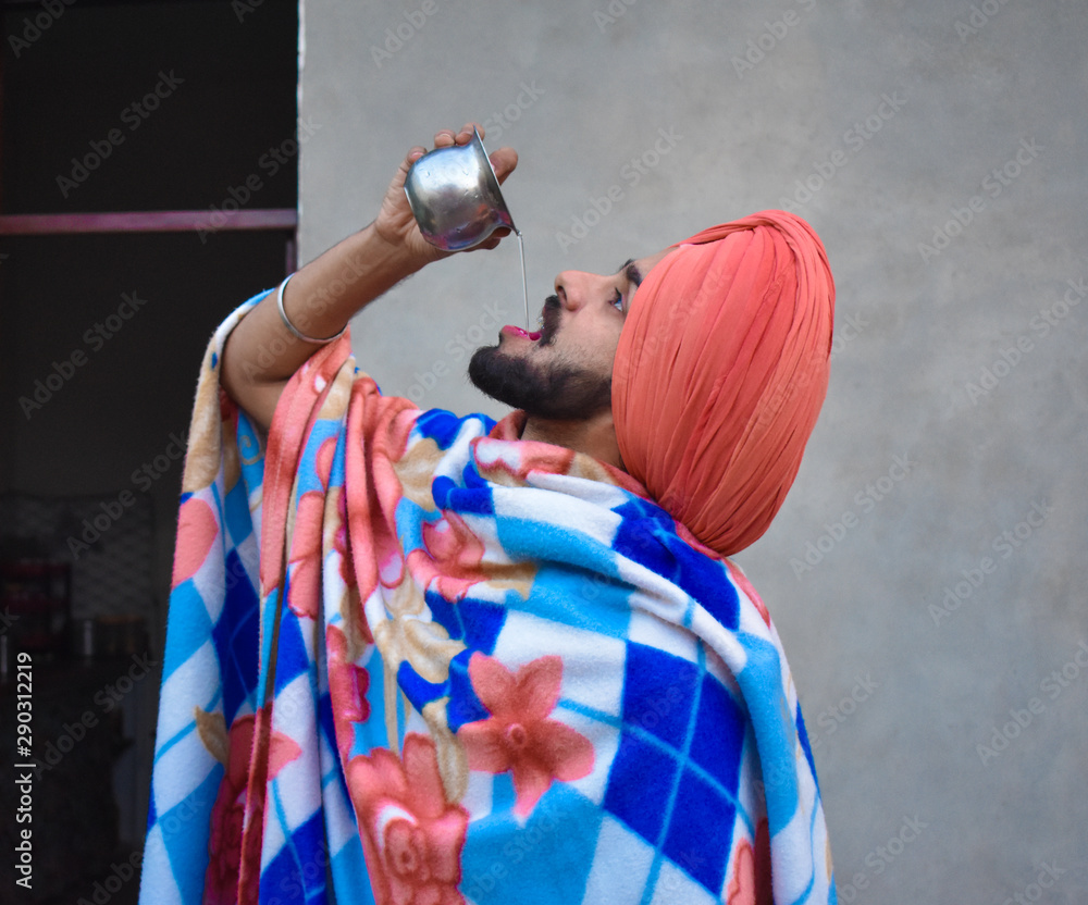 An Indian Punjabi boy drinking water in village style in an Indian ...