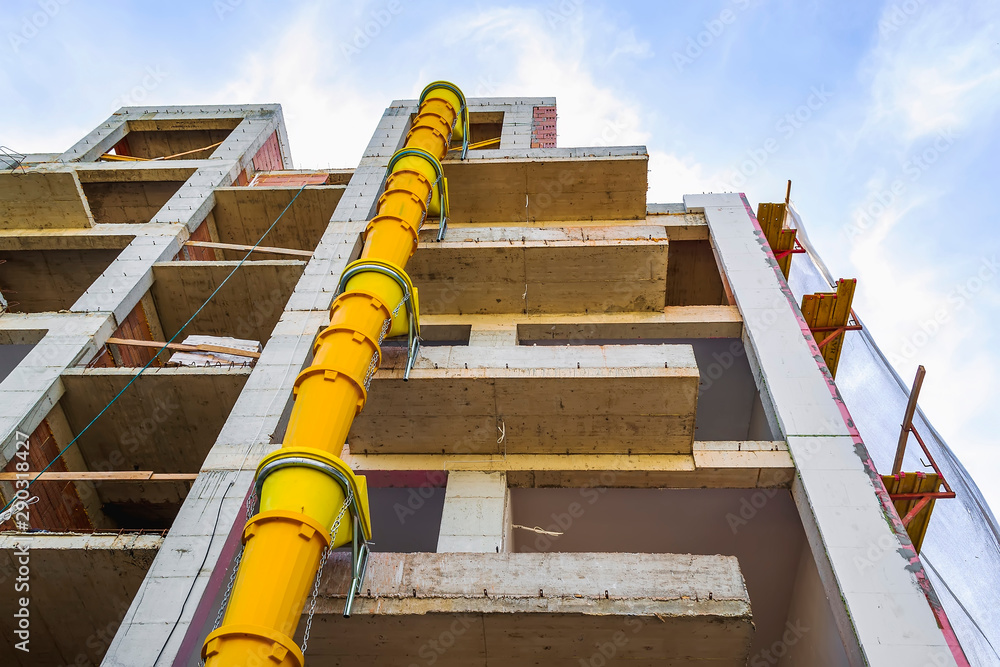 Suspended sections of yellow garbage chute on a facade of building ...