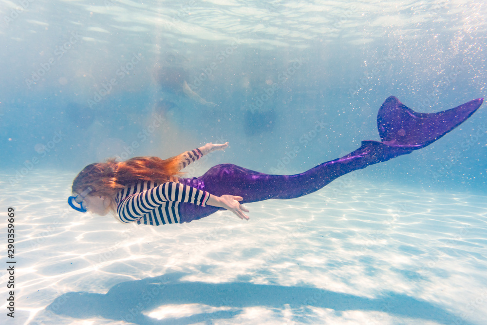 Girl on family vacation swimming gracefully in pool wearing mermaid ...