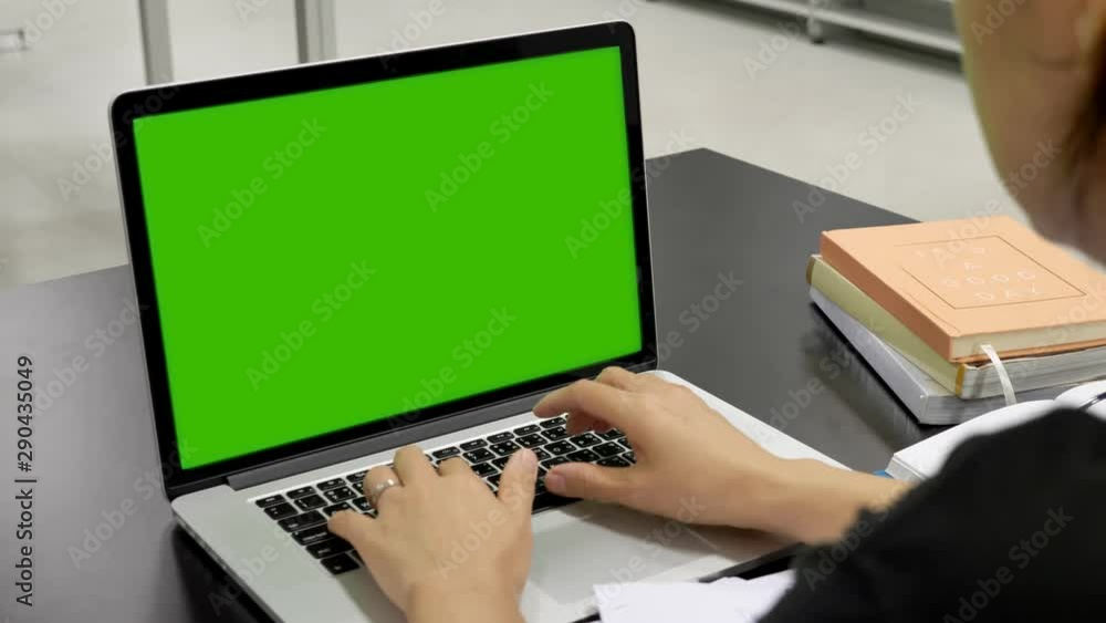 Over the shoulder shot of Asian woman typing and looking at laptop ...