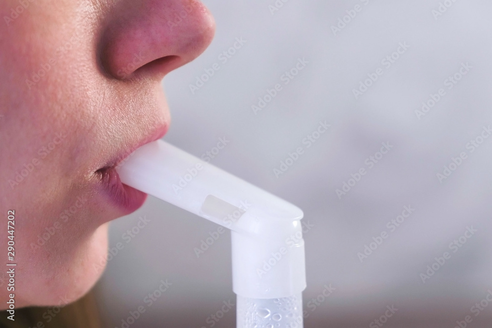 Use nebulizer and inhaler for the treatment. Young woman inhaling ...