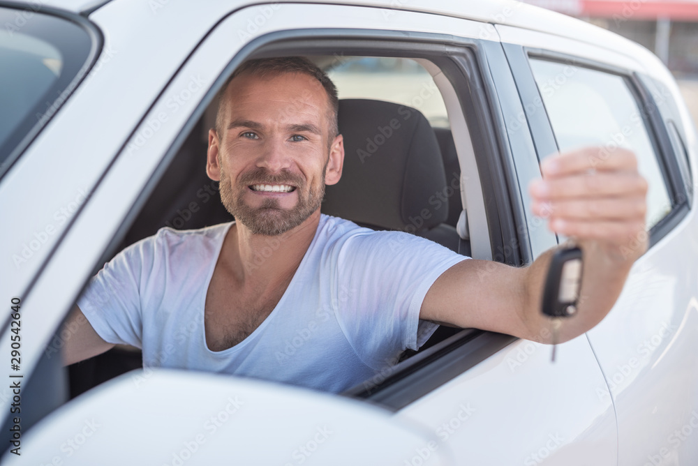 A man in a white car shows a key. Buying or renting a car - concept ...
