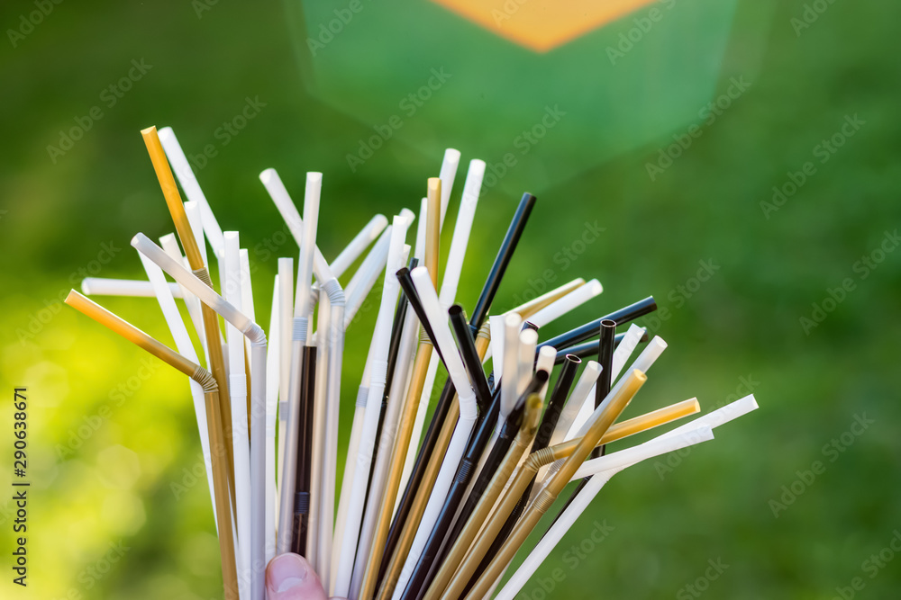 Hands holding plastic straws on green grass background. Plastic ...