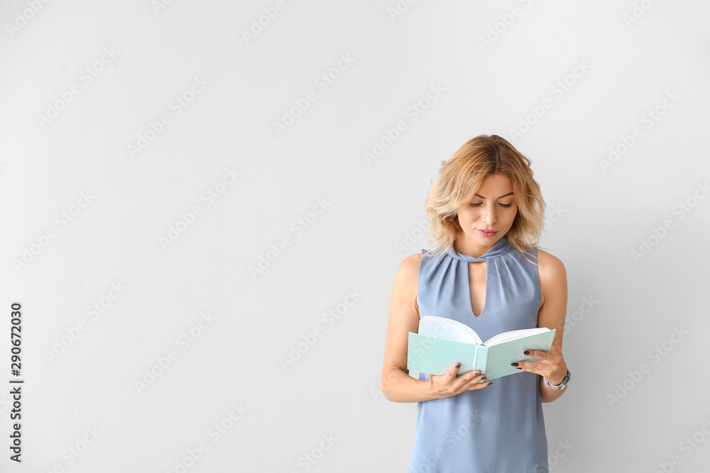 Portrait of beautiful woman with book on light background Stock Photo ...
