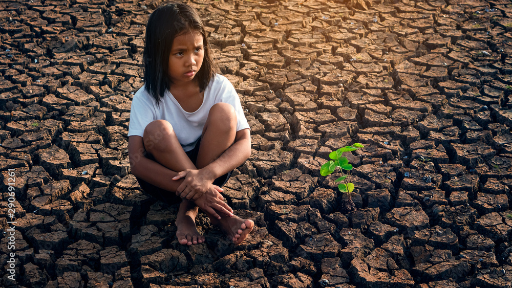 Sad girl sitting on dry soil with small trees that grow beside him ...