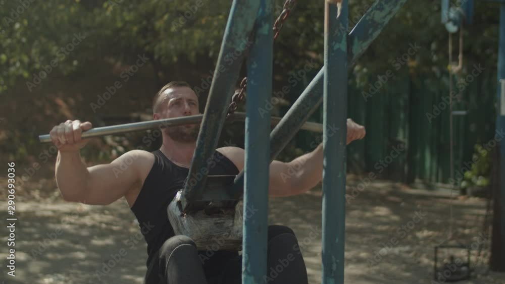 Handsome muscular bodybuilder exercising and flexing muscles on lat pulldown cable machine in ...