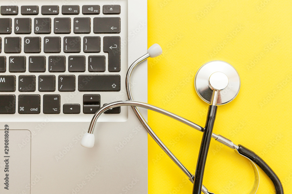 Stethoscope keyboard laptop computer isolated on yellow background ...