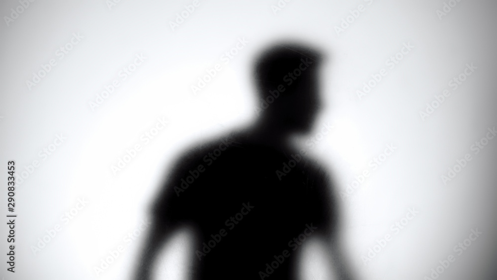 Silhouette of trapped man standing behind glass wall, room escape ...