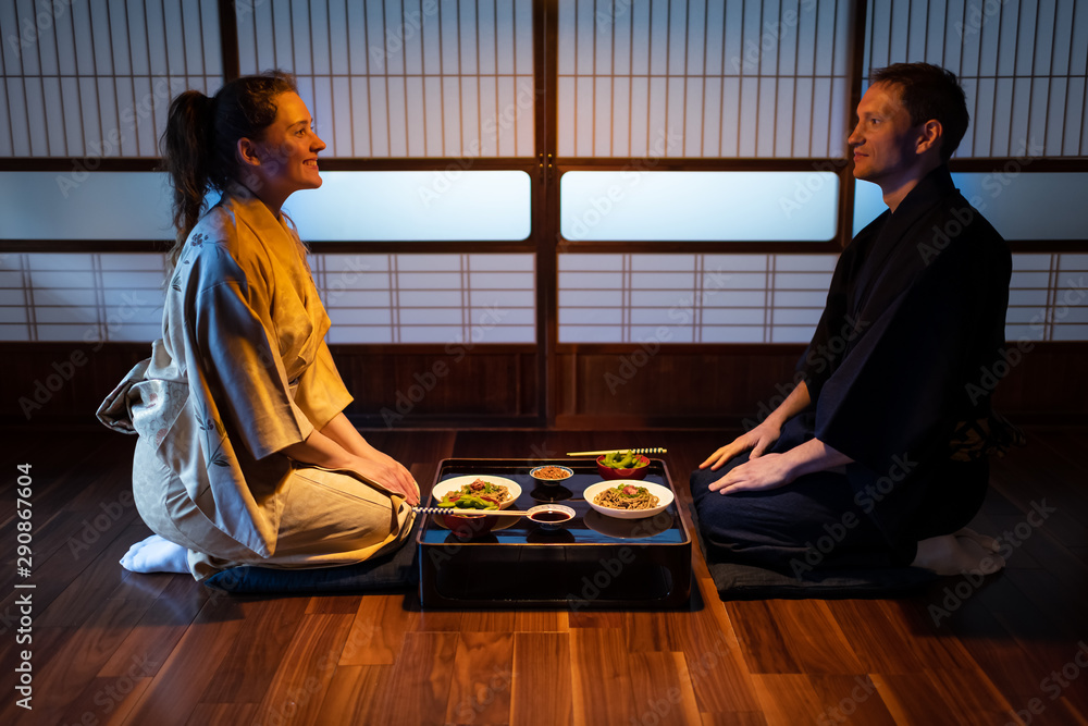 Young happy smiling couple seiza sitting on floor pillows with ...