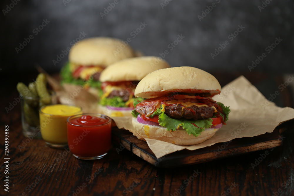 Beef burger in dark tone with low key light on wood plate and dark ...