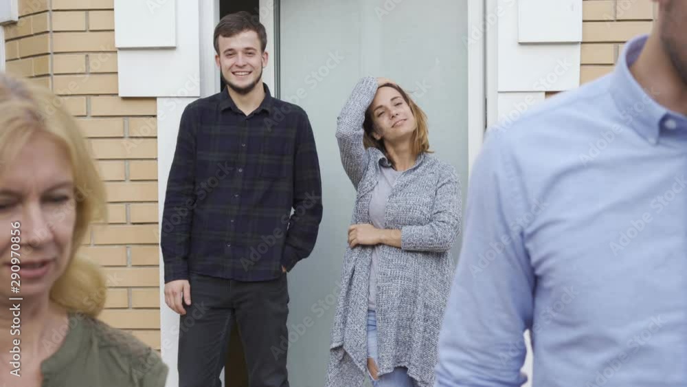 Happy family standing at doors and waving while their guests leaving ...