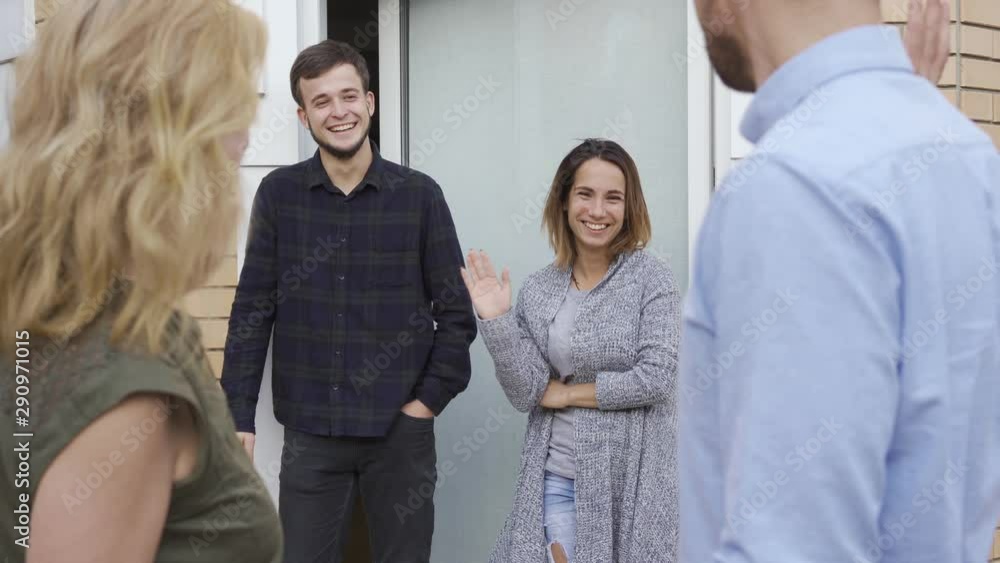 Pleasant caucasian family standing at doors, waving and smiling. Guests ...