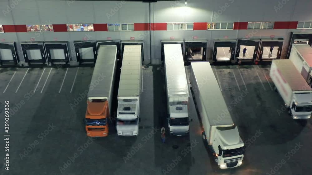 Aerial side view of a semi-trailers trucks standing at the ramps of the ...