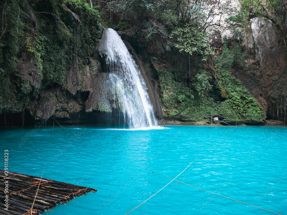 Waterfall with bamboo raft on the turquoise water pool at Kawasan Falls ...