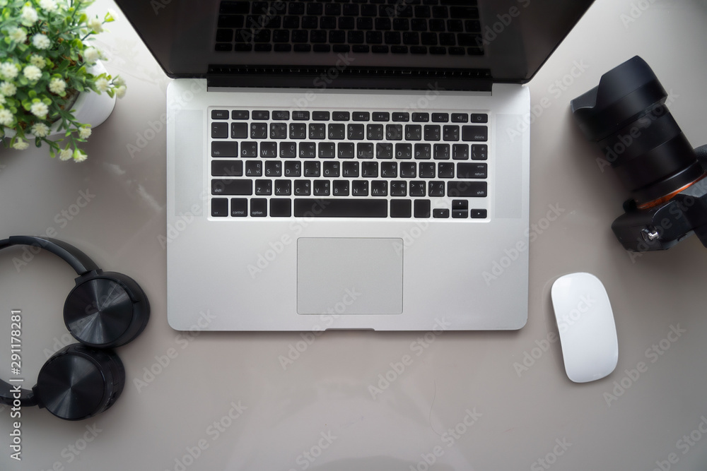 Top view a laptop with camera on white table with mouse and headphone ...