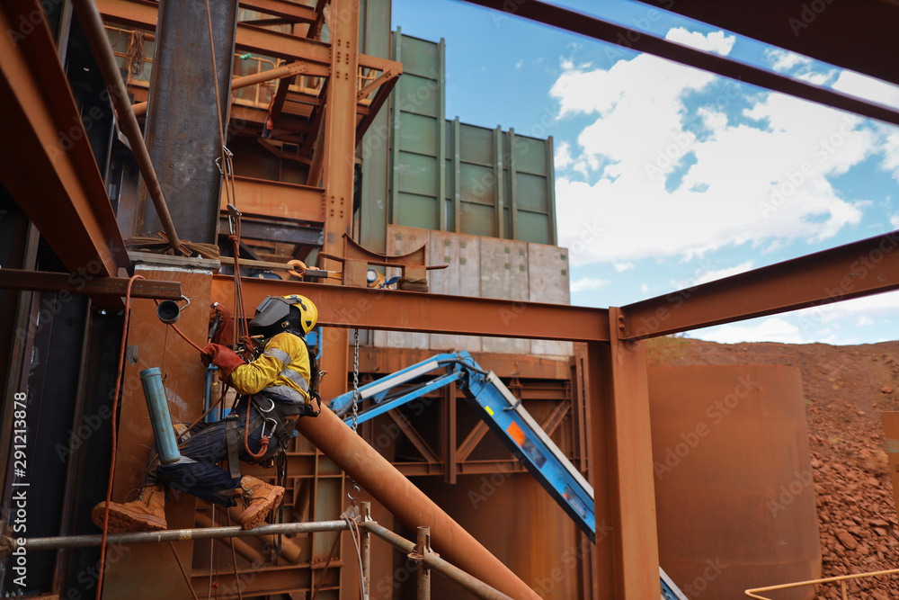 Wide angle shoot of rope access welding abseiler wearing fall safety ...