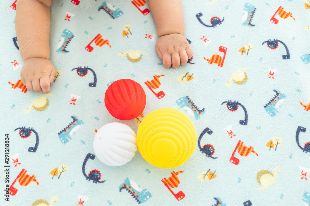 Baby playing with colorful toy rubber balls in the crib in a bright ...