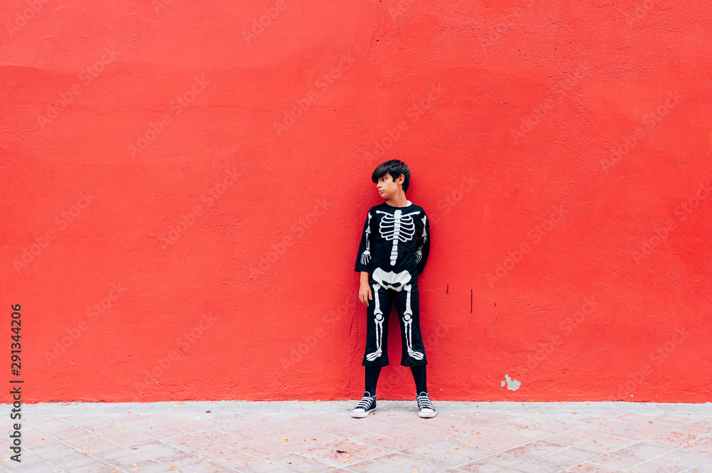 Boy in skeleton costume standing in street on the red background Stock ...