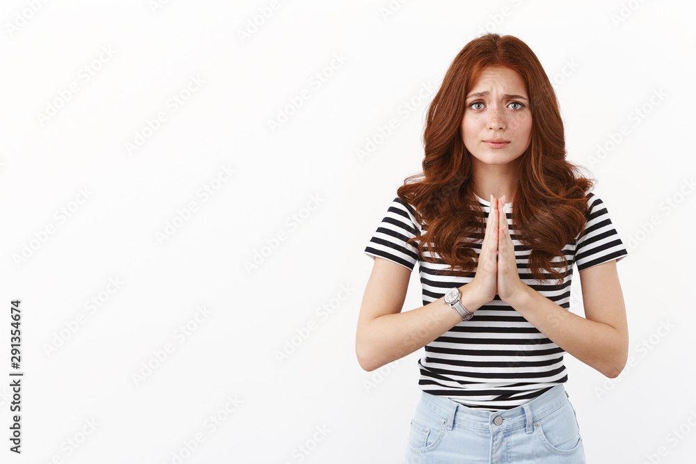 Hopeful earnest young ginger girl in striped t-shirt feeling hopeless ...