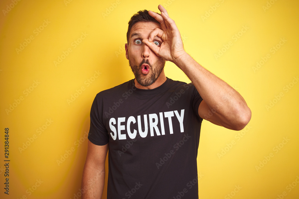 Young safeguard man wearing security uniform over yellow isolated ...