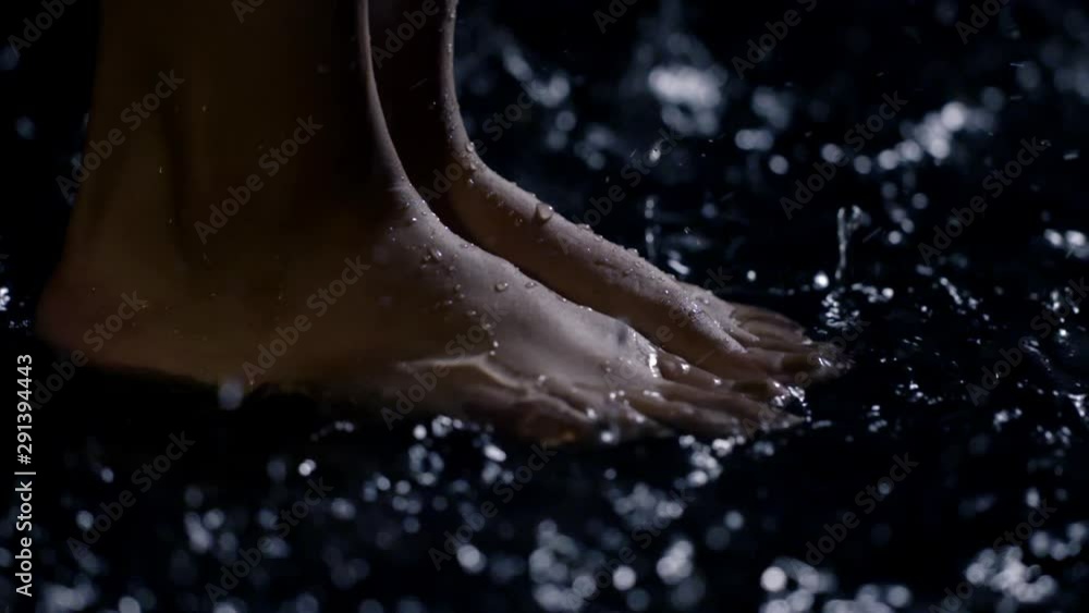 CU dark-skinned woman's bare feet splash down as she jumps into shallow ...