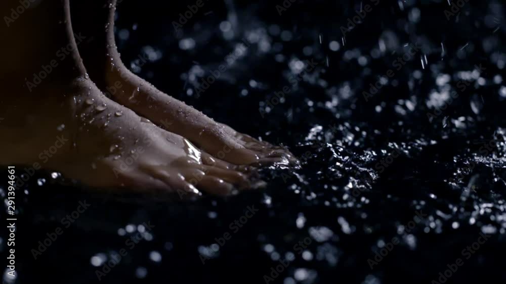 CU dark-skinned woman's bare feet splash down as she walks into shallow ...