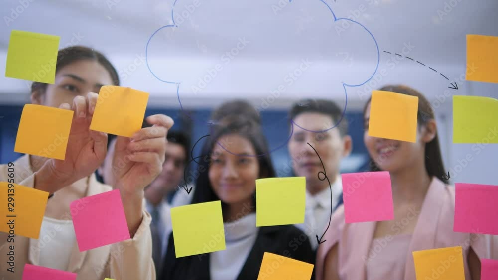 Asian business team brainstorming and sharing ideas with sticky notes ...